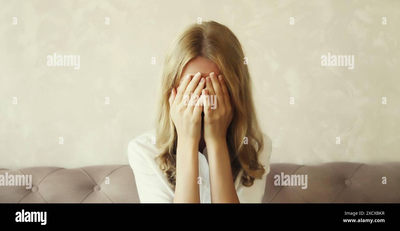 Upset sad crying woman covering her eyes and face with her hands while ...