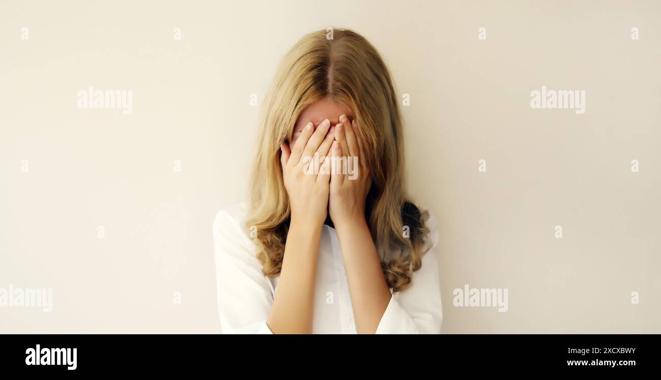Upset sad crying woman covering her eyes and face with her hands while ...