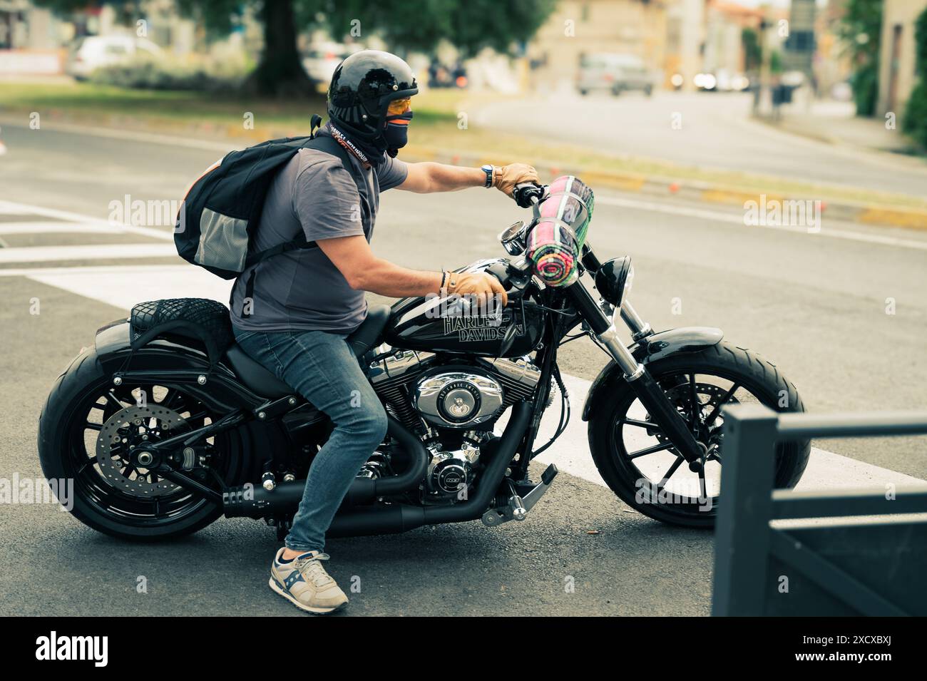 A man riding a Harley Davidson motorcycle on a city street Stock Photo ...