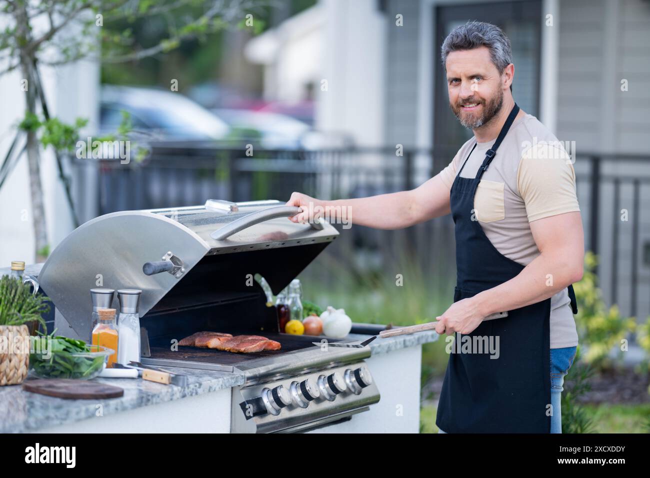 Hispanic man cooking on barbecue in the backyard. Chef preparing ...