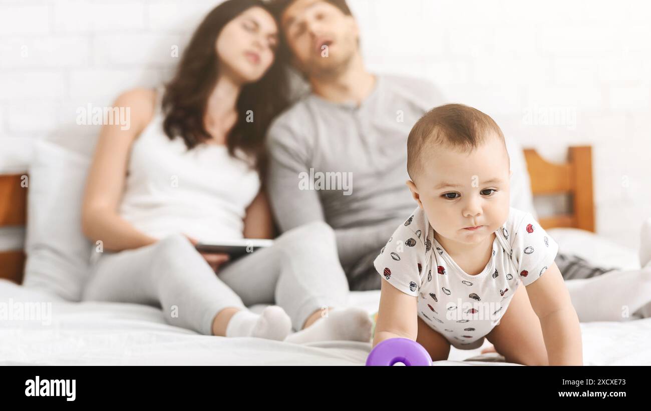 Baby Crawling Towards Parents Sleeping On Bed Stock Photo - Alamy