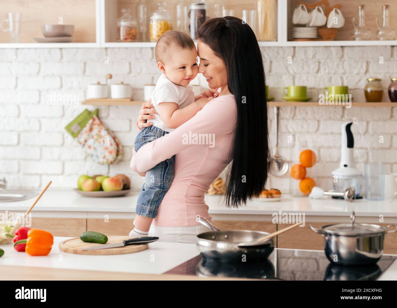 Woman Holding Baby in Kitchen, Bonding While Cooking Stock Photo - Alamy