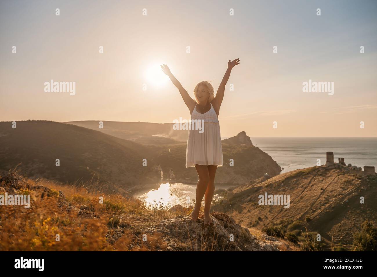 woman standing hill with her arms raised in the air, looking up at the ...
