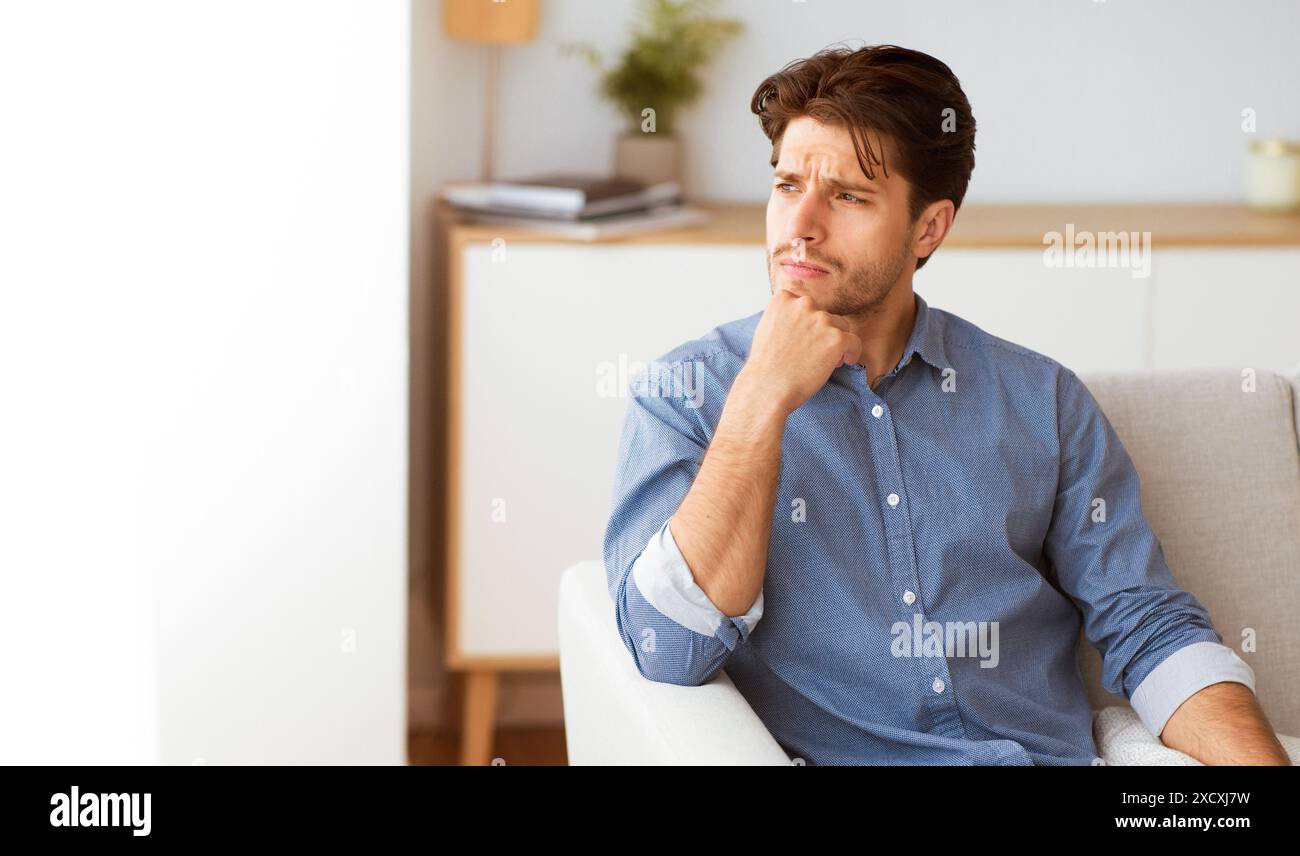 Man Thinking While Sitting On A Couch Indoors Stock Photo - Alamy