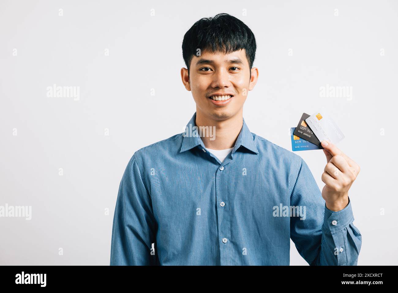 Portrait Asian smiling young man holding two debit credit cards in his ...