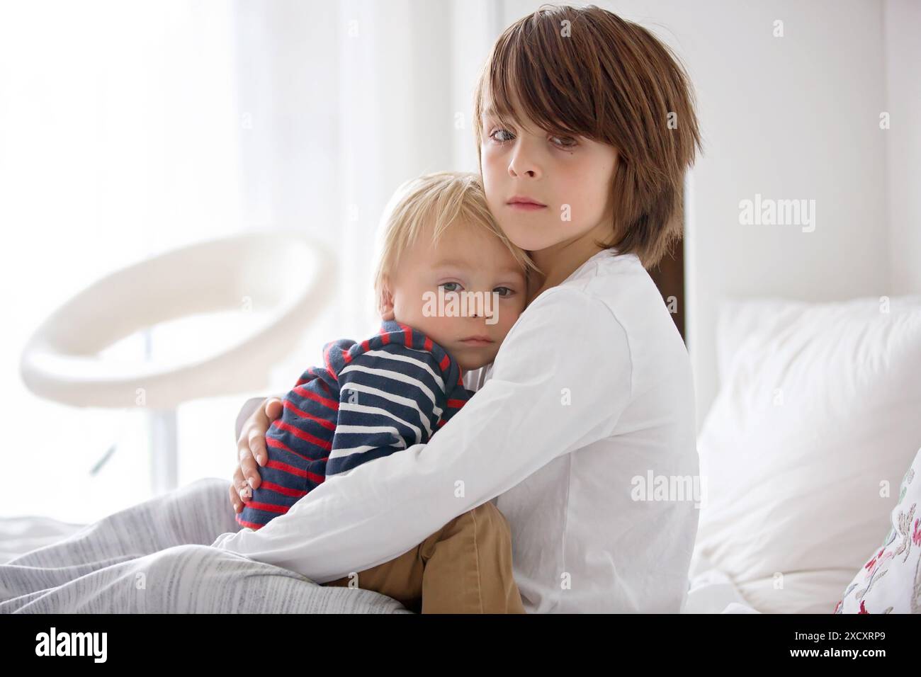 Sweet preteen chil and his cute little brother hugging at home in sunny ...