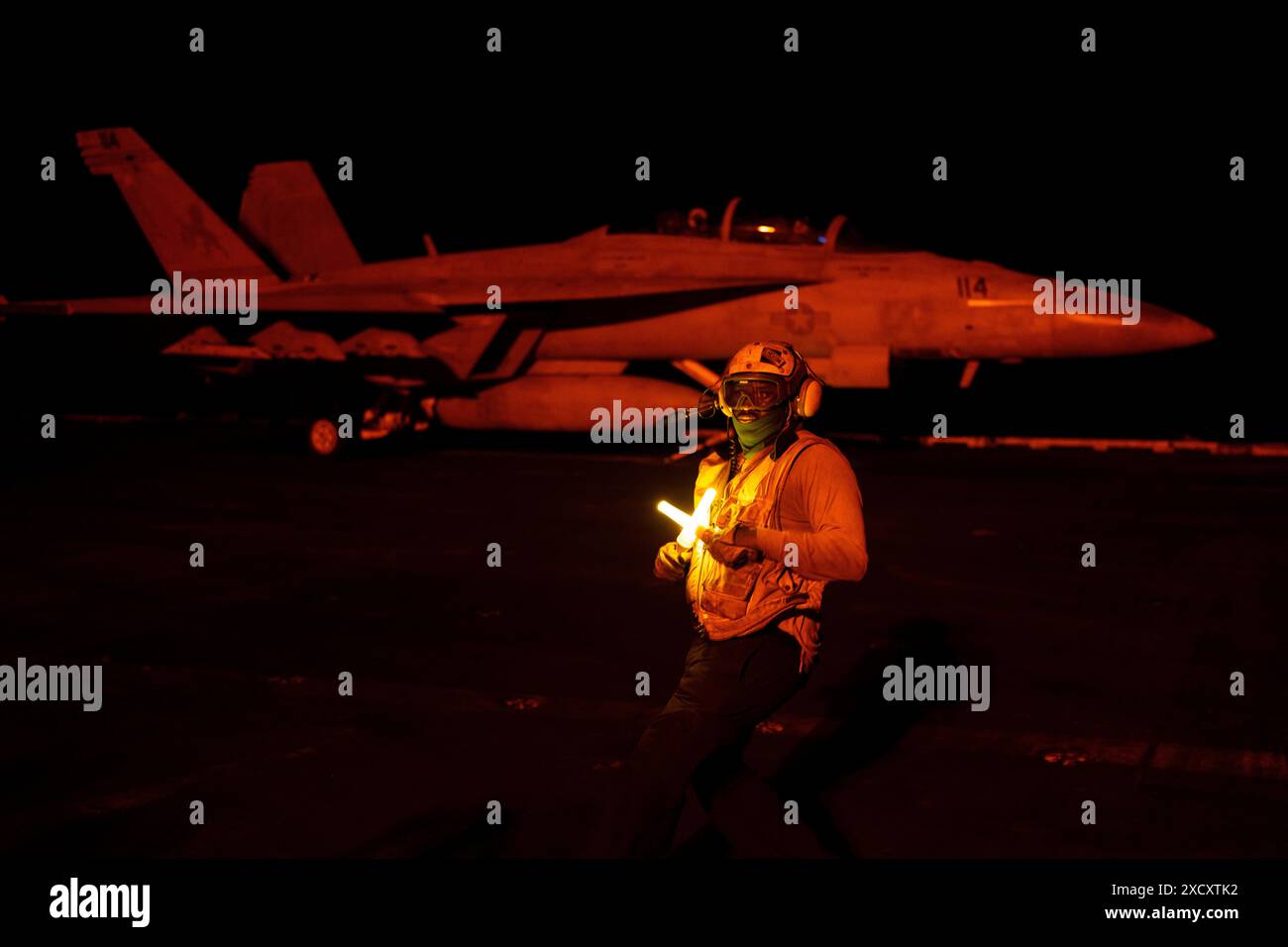 An aircraft handling officer directs a fighter jet during takeoff ...
