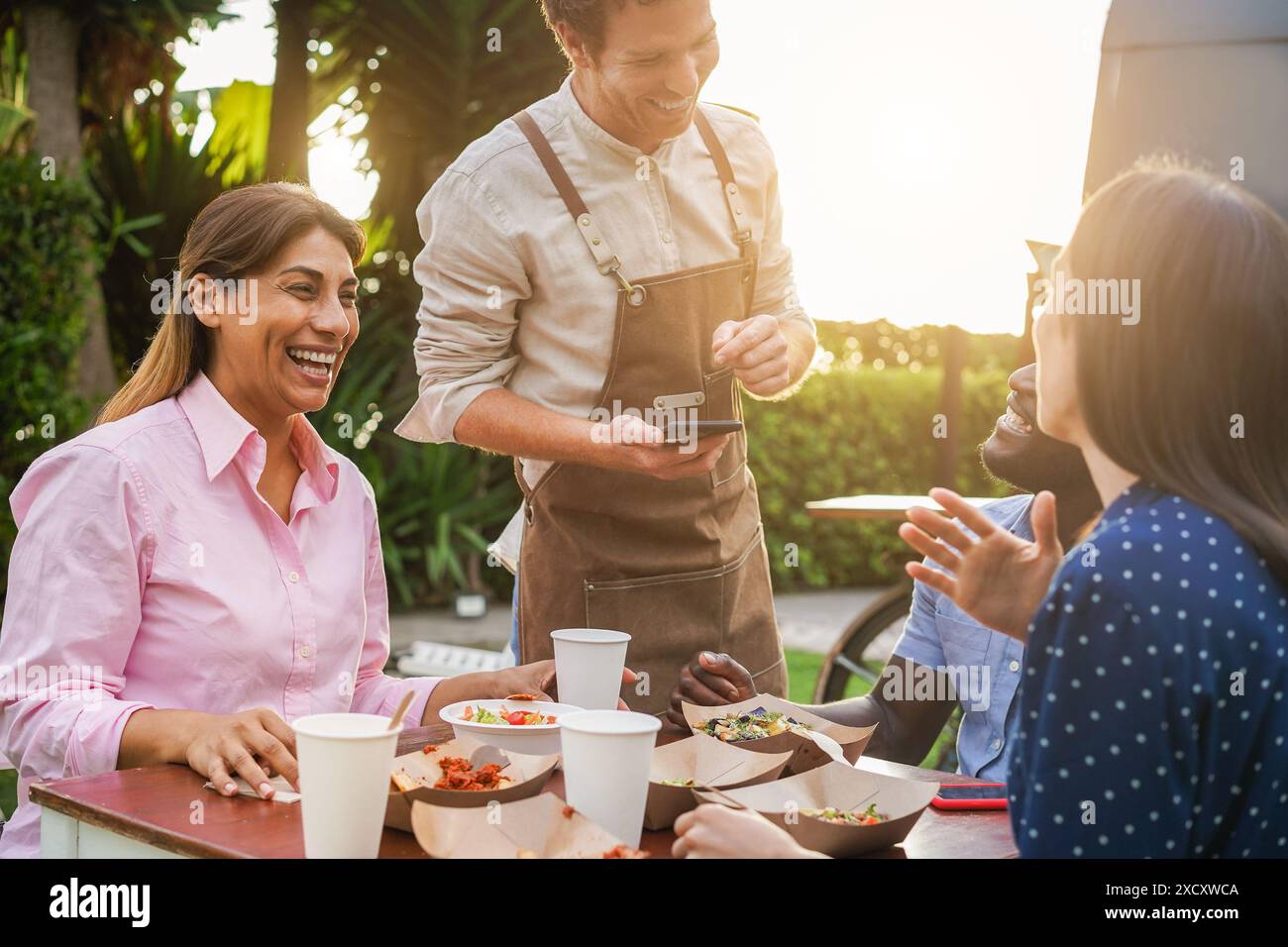 Multiracial people eating at food truck restaurant outdoor during ...