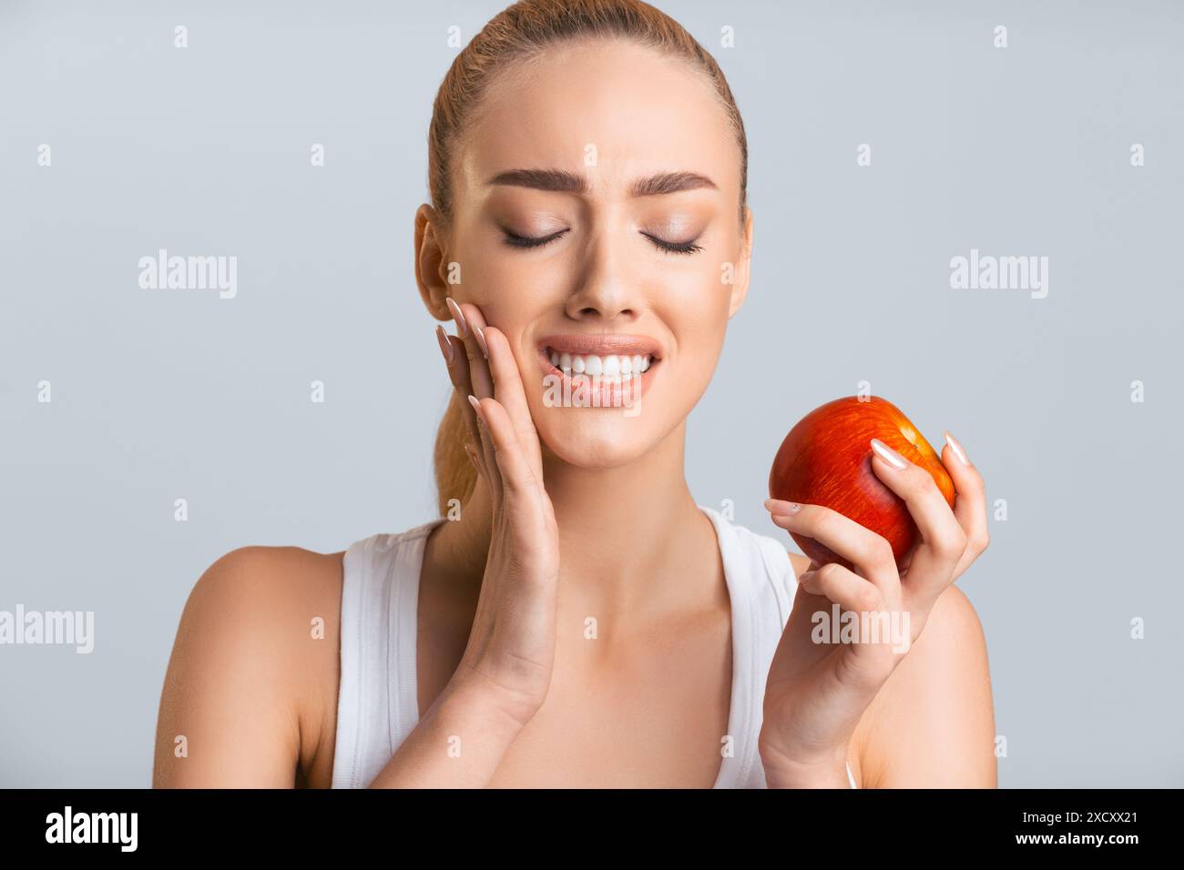 Woman Holding Red Apple And Touching Her Cheek Stock Photo - Alamy