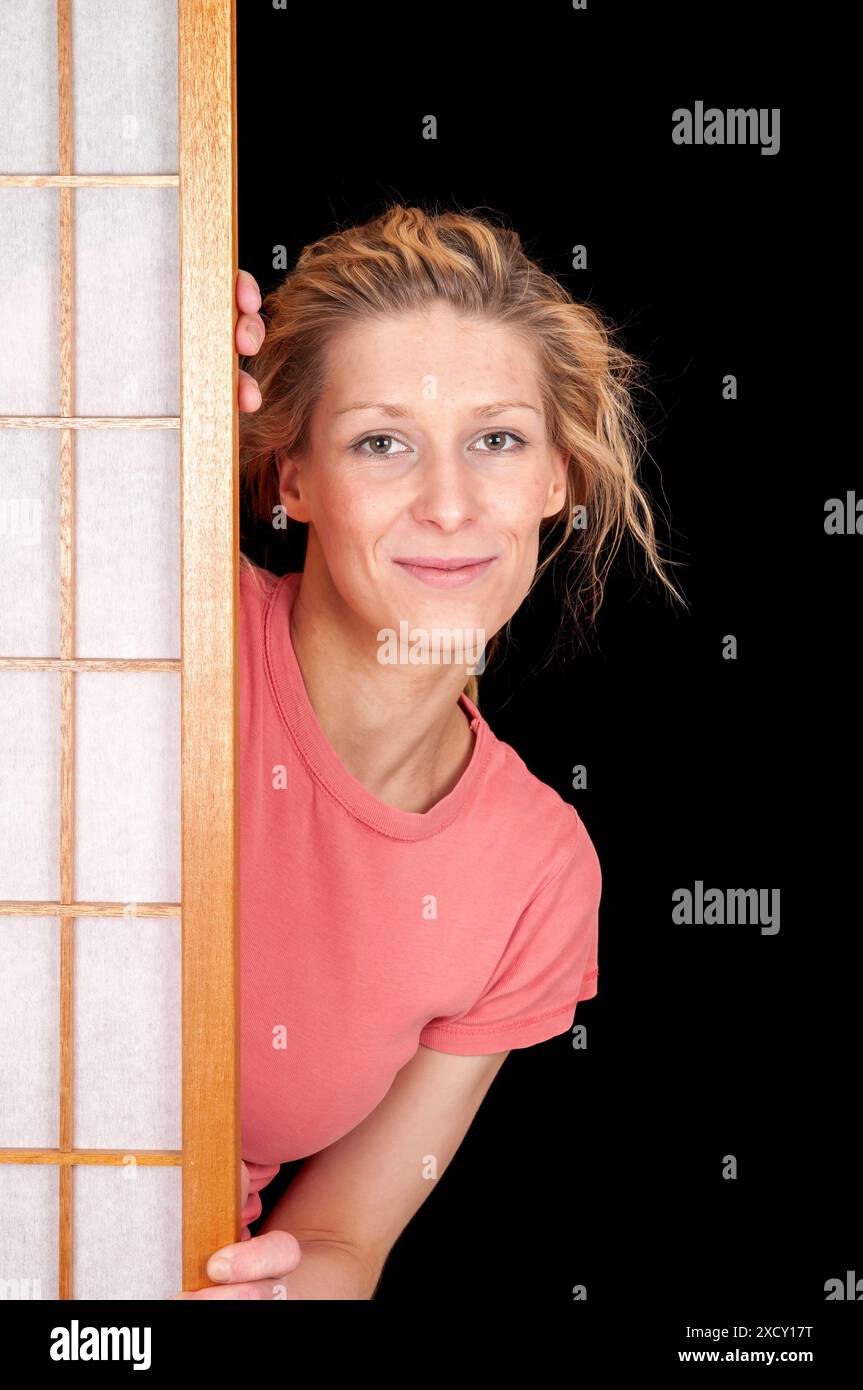 Upper body portrait of a young blonde woman standing behind a screen ...