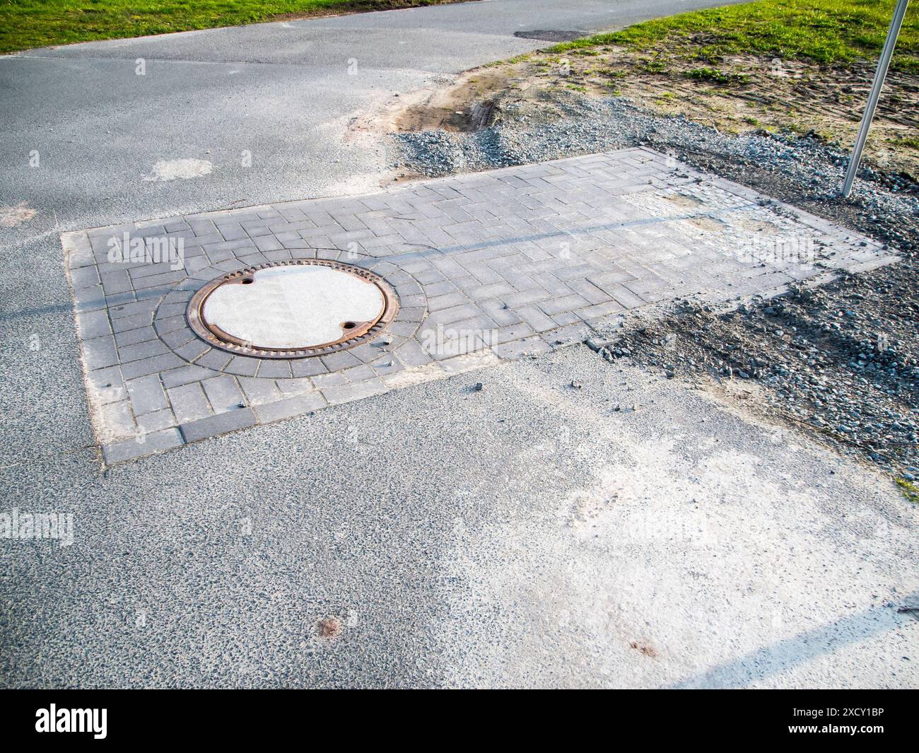 Newly constructed shaft with manhole cover on a rural asphalt road in ...