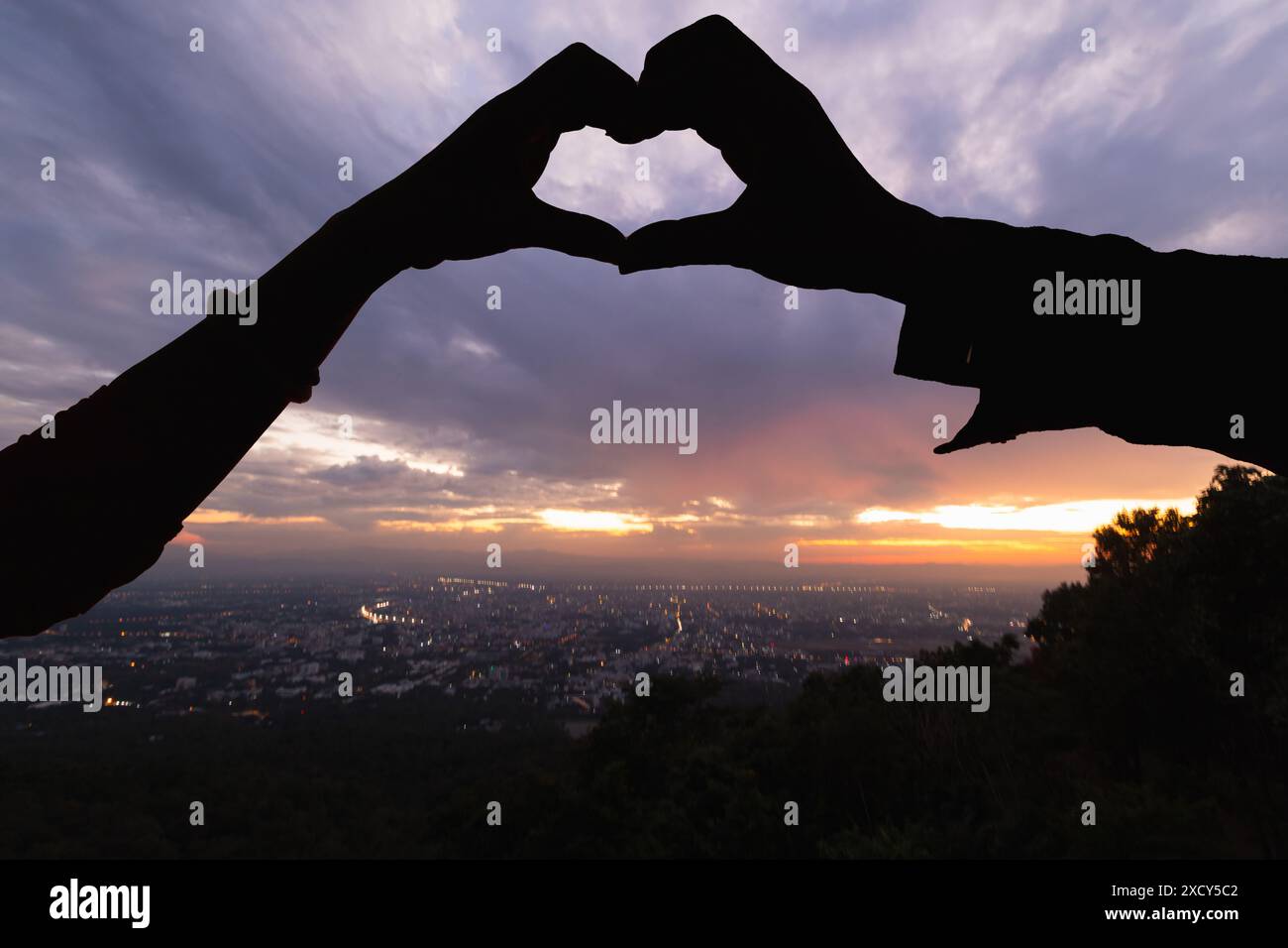 Silhouette couple hands raised up make heart shape on beautiful evening ...
