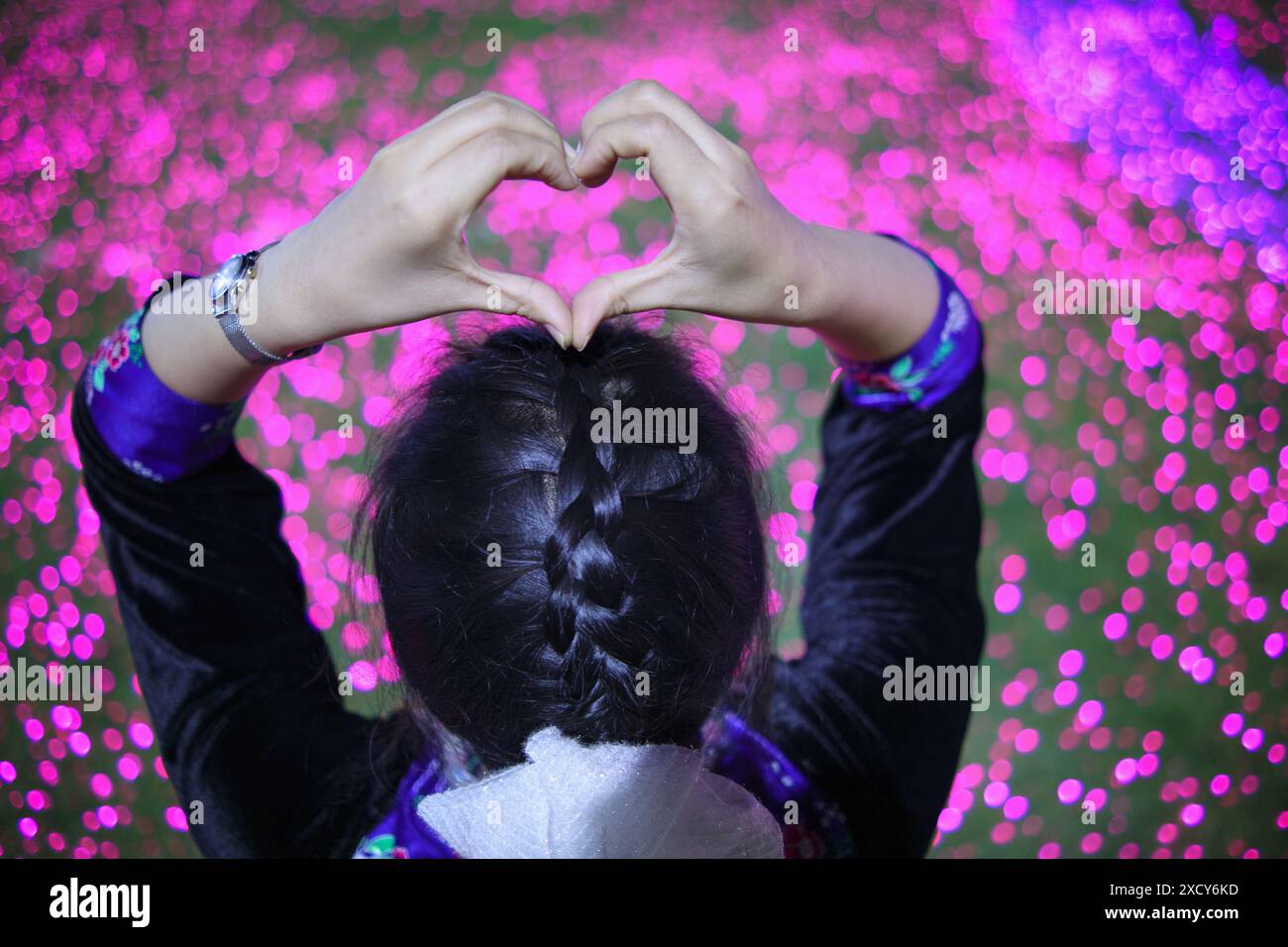 woman raises her hands to make heart symbol that represents love and ...