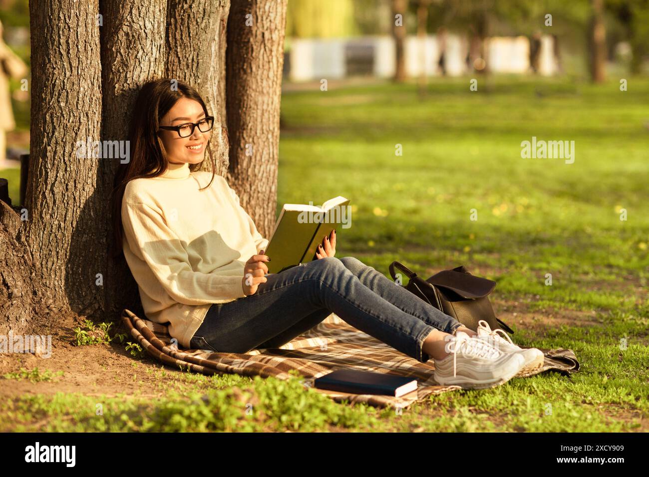 Young Chinese Woman Reading Book Under Tree Stock Photo - Alamy