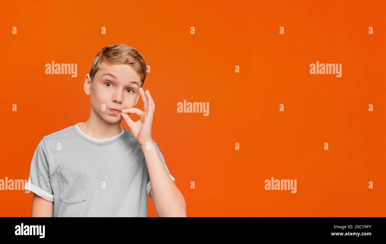 Cute teenager boy locking mouth like zip-lock Stock Photo - Alamy