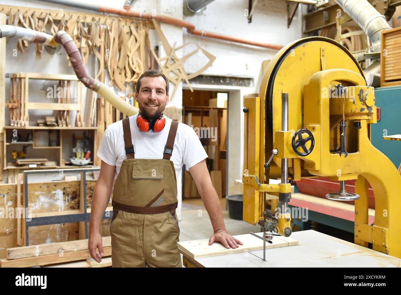 portrait of a carpenter in work clothes and hearing protection in the ...