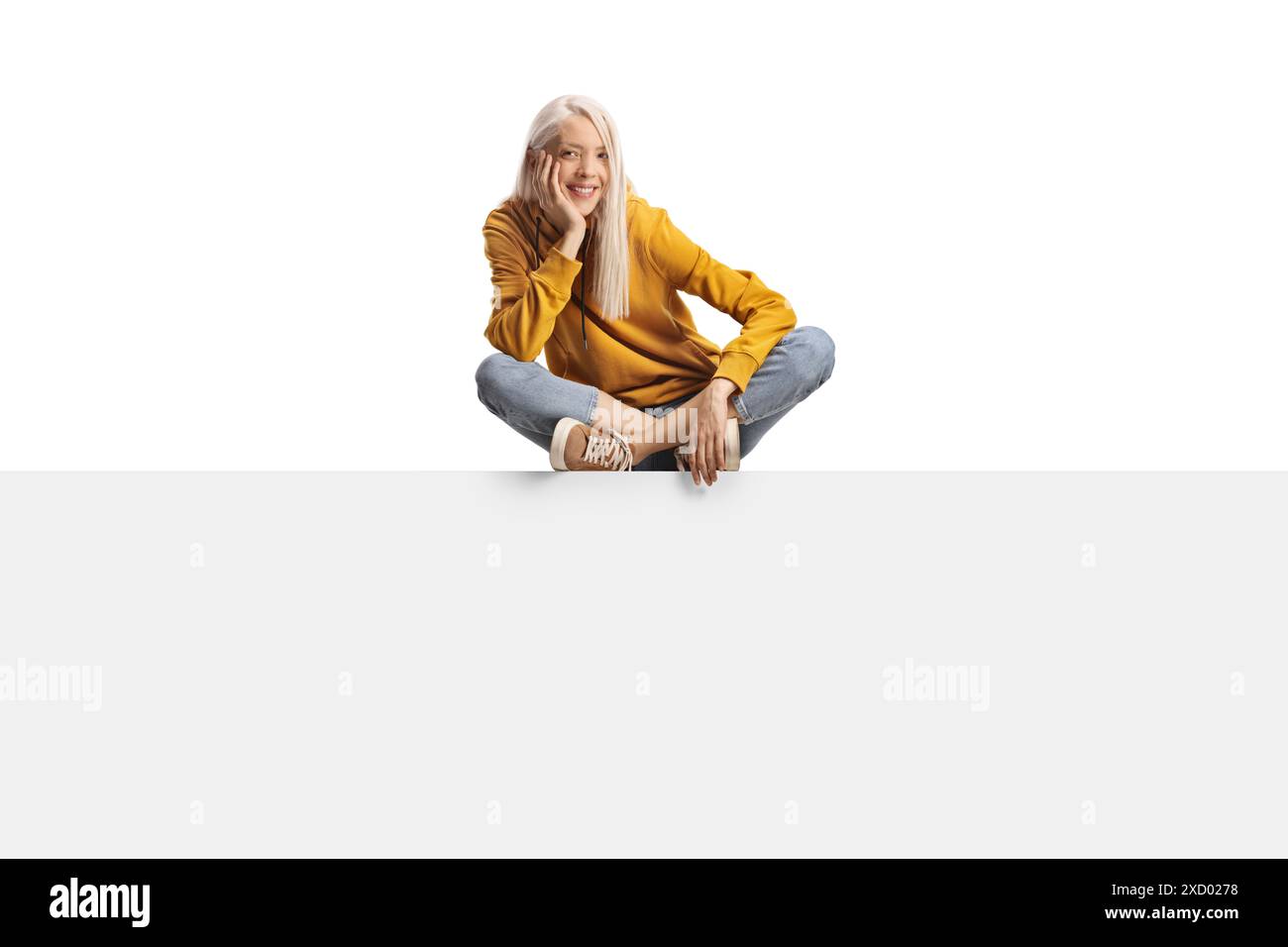 Young woman sitting on a blank panel with crossed legs isolated on ...