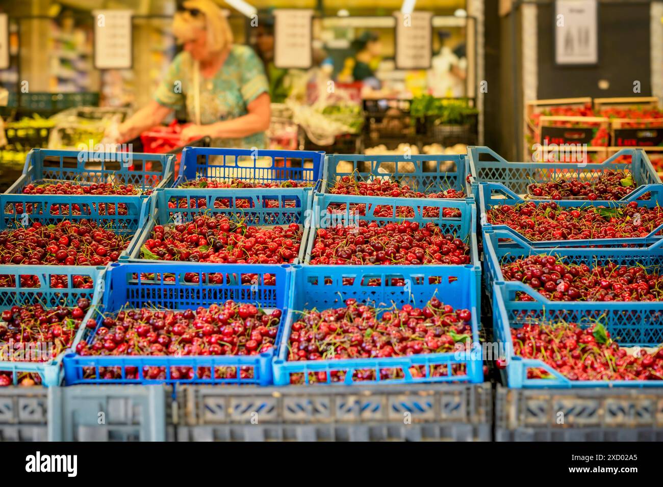 Fresh cherries in boxes at a farmers market, blurred background of ...