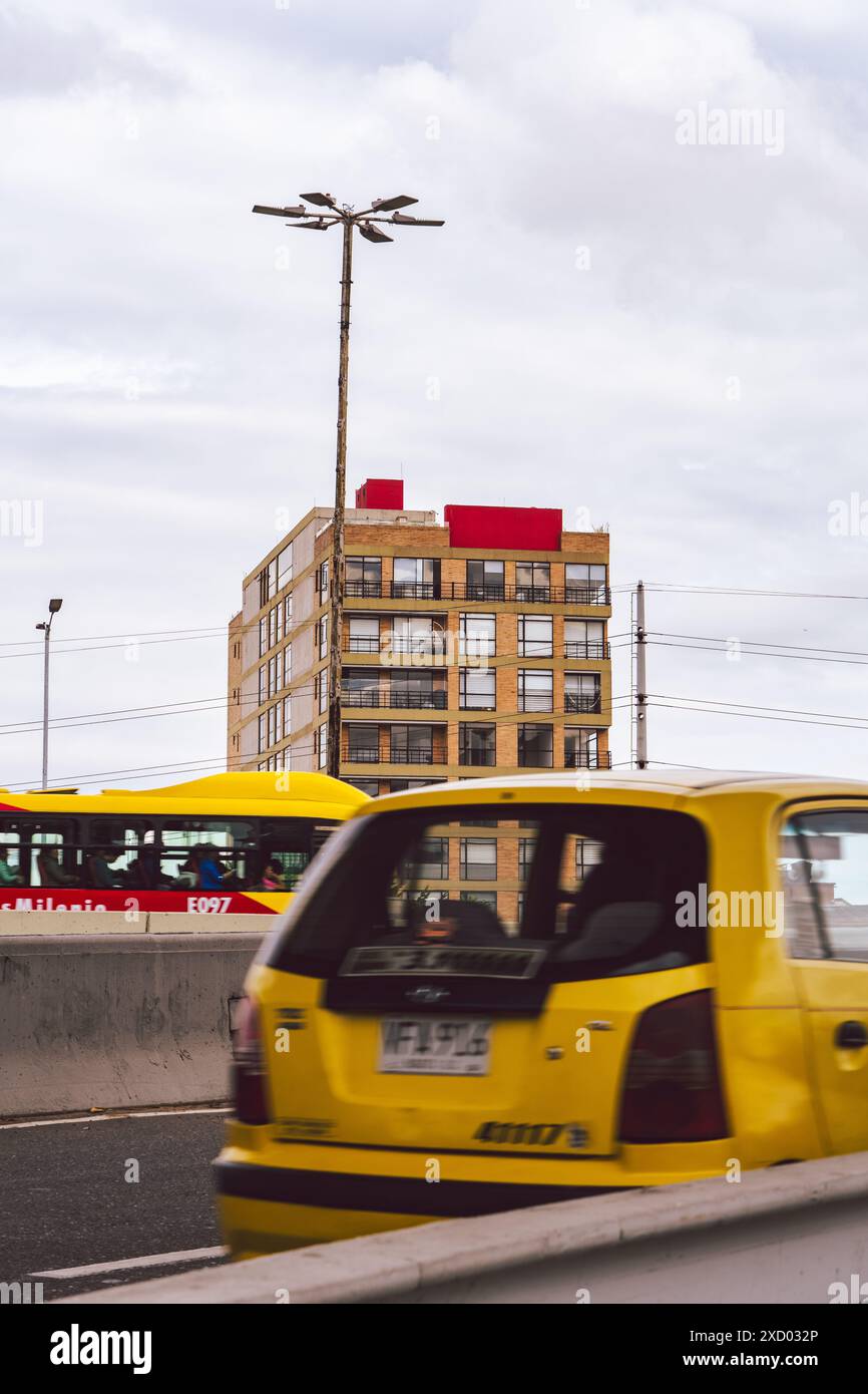 Yellow taxi and TransMilenio bus on a Bogotá street with a modern ...