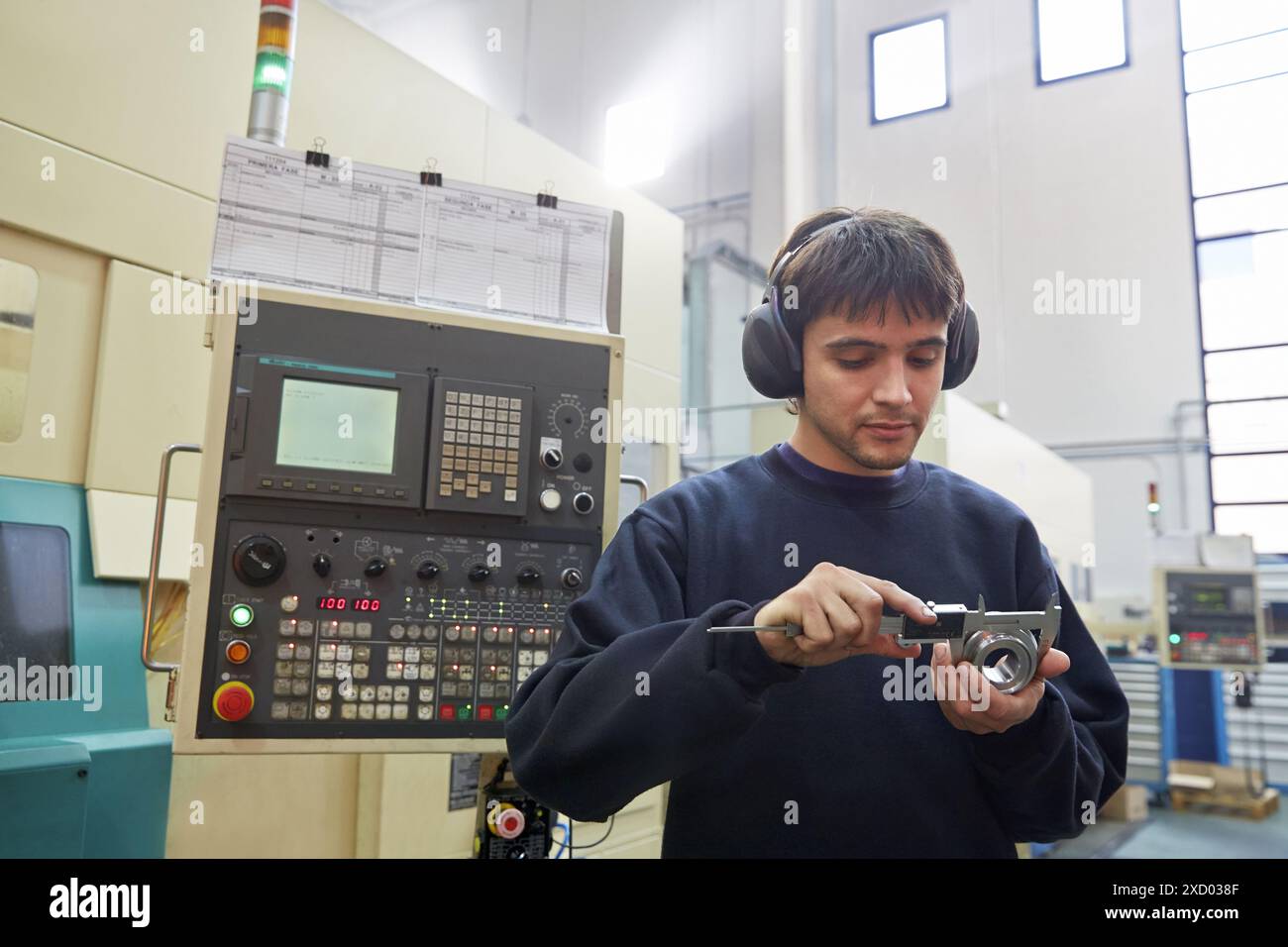 Worker measuring with caliper. Area automated CNC lathes. Machined ...