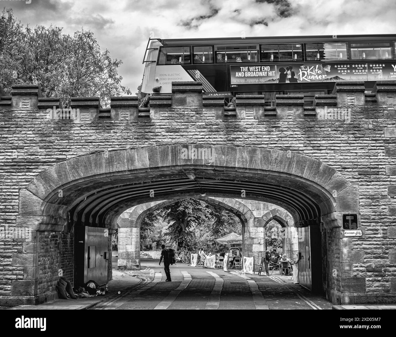 A bus passes over a bridge and underneath an archway a homeless man ...