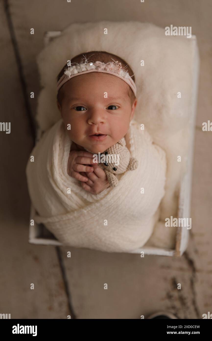 Top view of a newborn baby eyes open on a bed under beige blanket and a ...