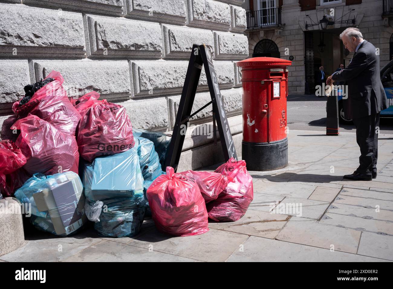 A man posts a letter in the postal box on Bell Yard in the City of ...