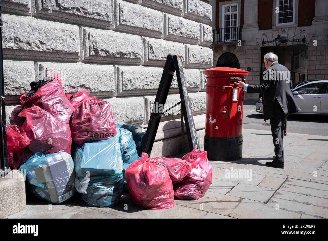 A man posts a letter in the postal box on Bell Yard in the City of ...