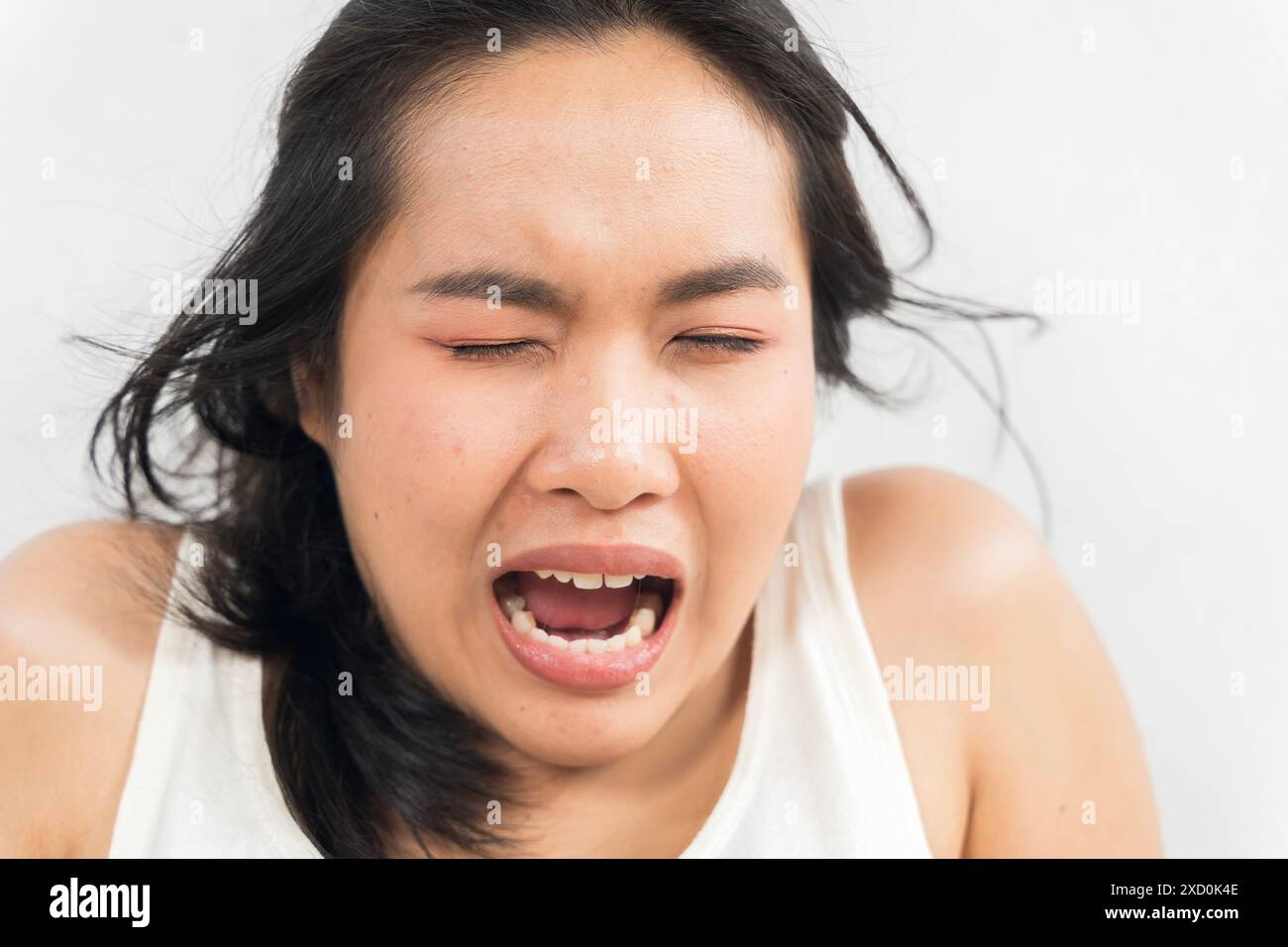 A woman with her mouth open and eyes closed. She is crying. Concept of ...