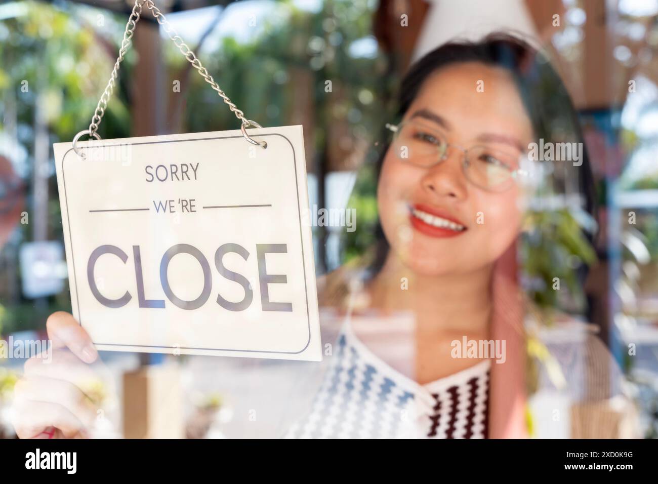 Caucasian female turning sign from open to closed on the entrance door ...