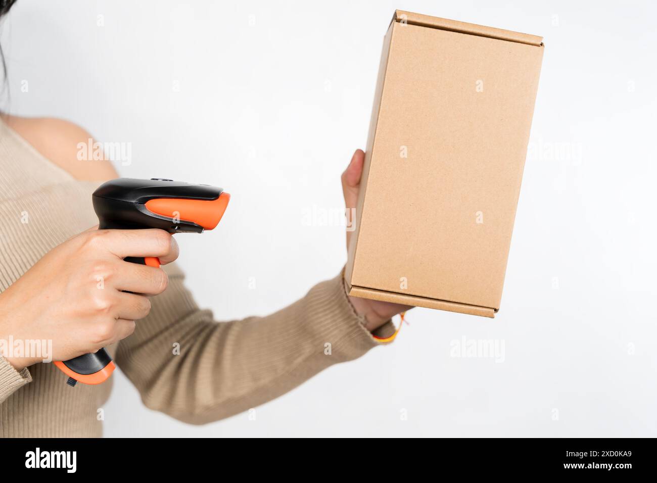 A woman is holding a cardboard box and a barcode scanner on a white ...