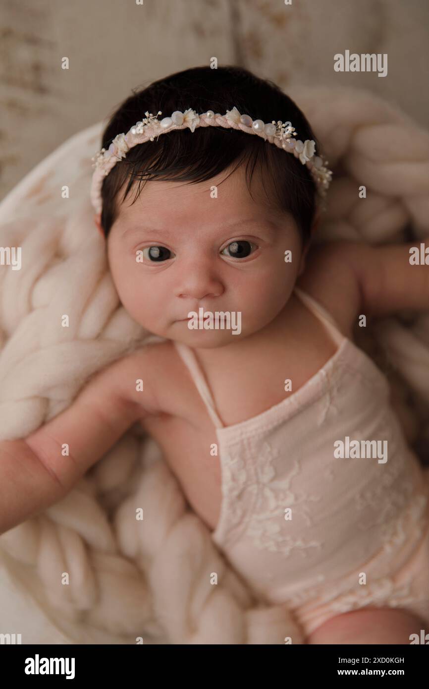 Top view of a newborn baby eyes open on a bed under beige blanket and a ...