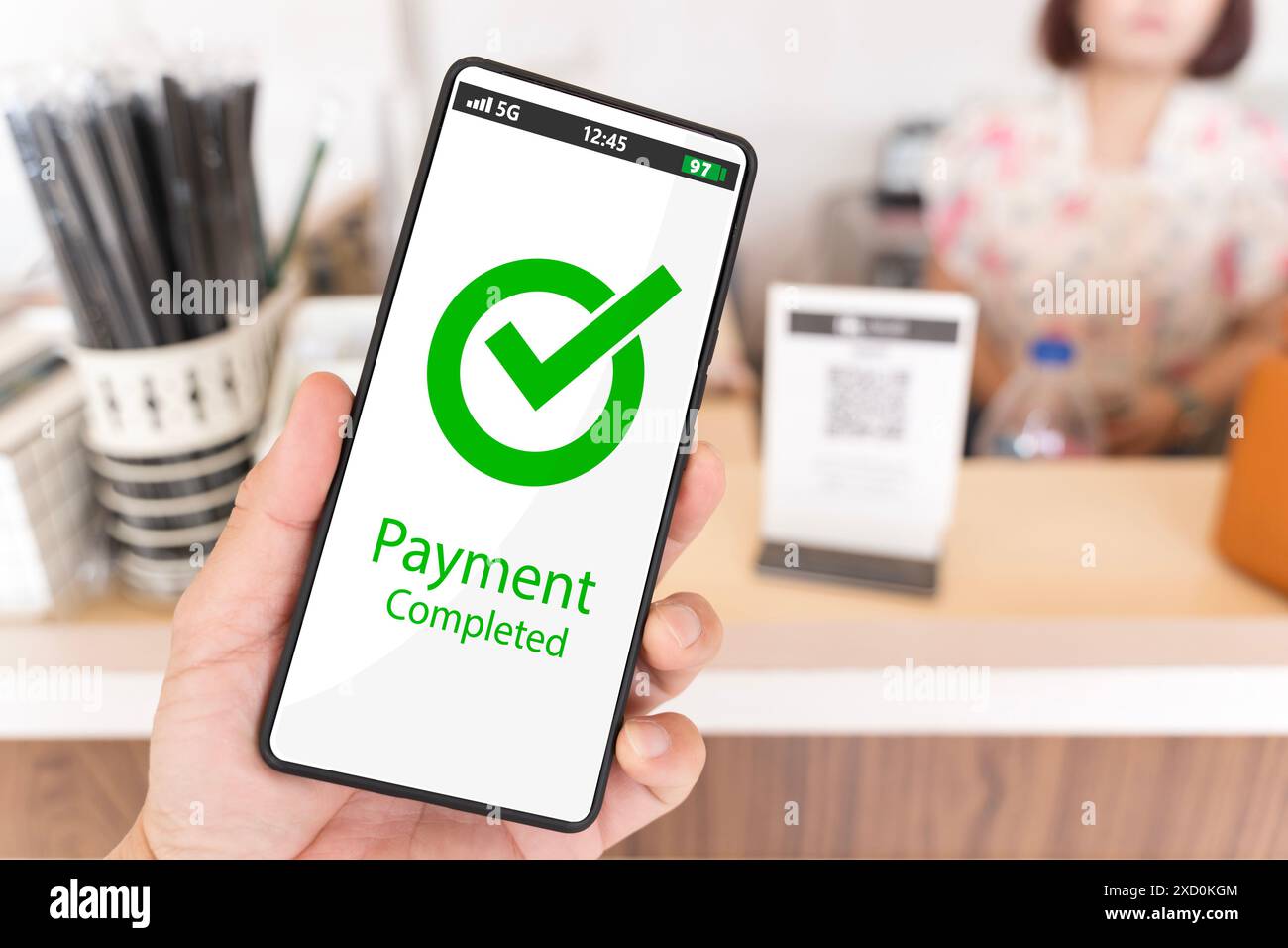 A person holding a cell phone with a green check mark on it that says ...