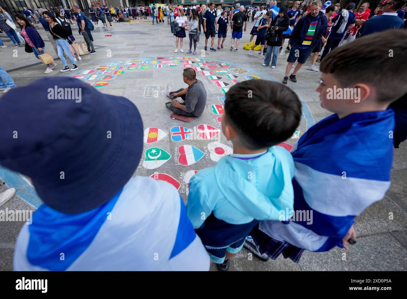A man paints heart shaped country flags that people put coins on as ...