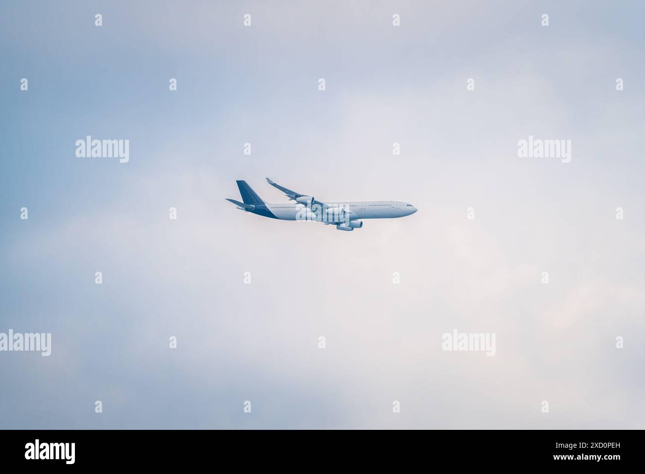 A commercial airplane flying high in the sky with a backdrop of clouds ...