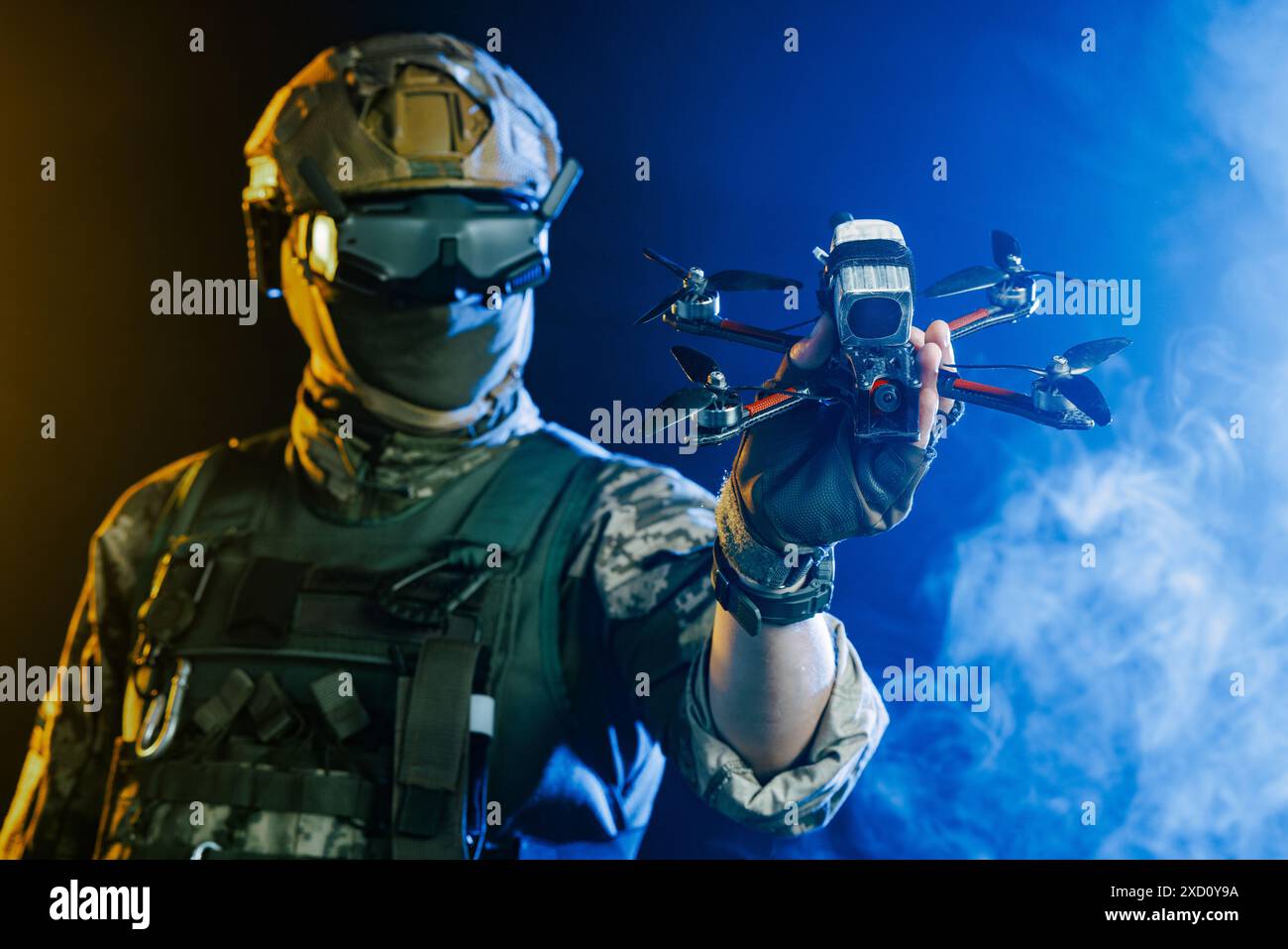 Soldier in gear holds drone against a red and blue smoky background ...