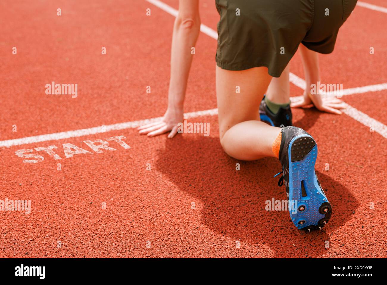 An athlete at the start line, poised for a sprint, concentrating on ...