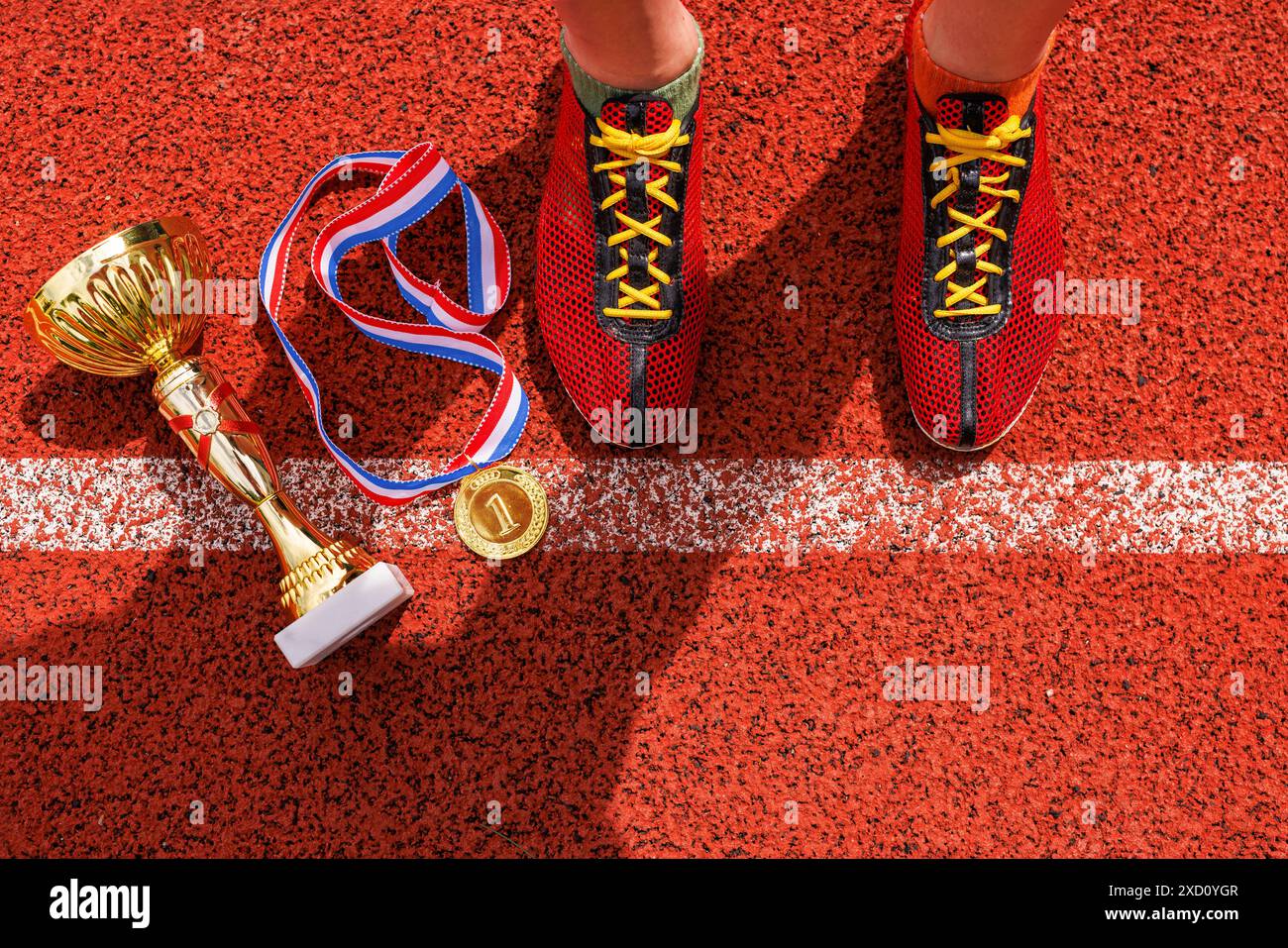 An athlete is standing on the track with a trophy and medal, with a red ...