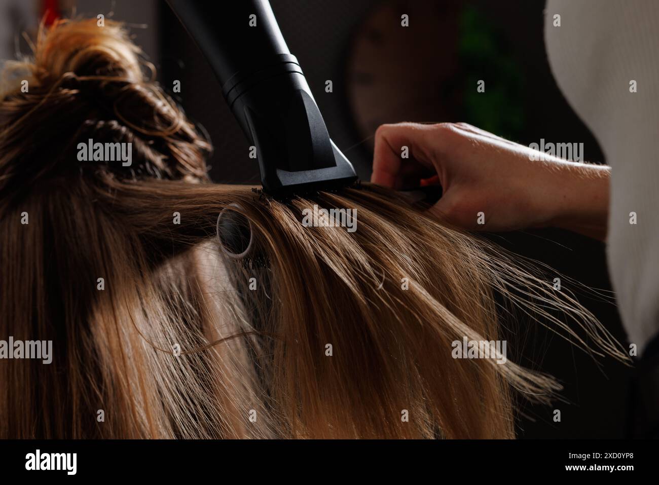 hairdresser drying hair with hair dryer and comb in beauty salon ...