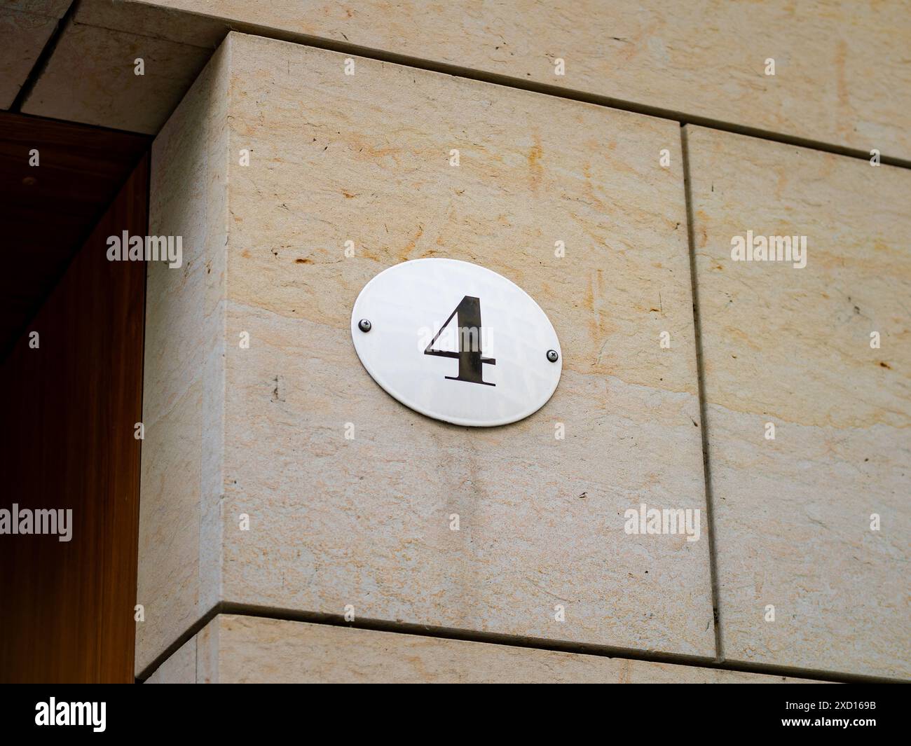 Number 4 on an exterior house wall. The metal plate is enameled and ...
