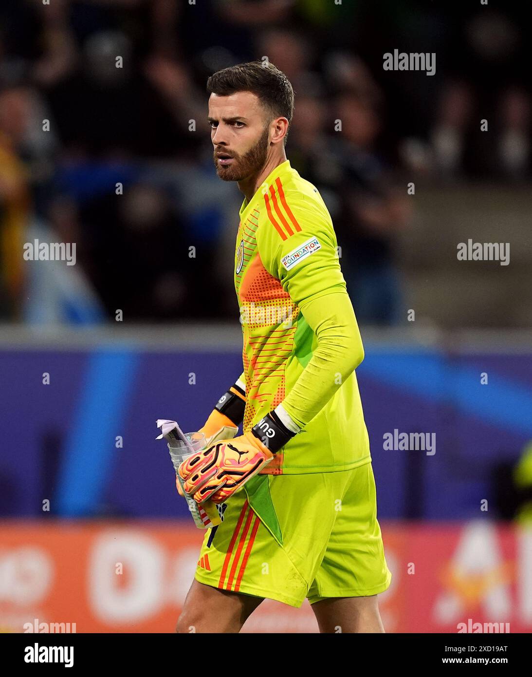 Scotland goalkeeper Angus Gunn collects cups thrown onto the pitch ...