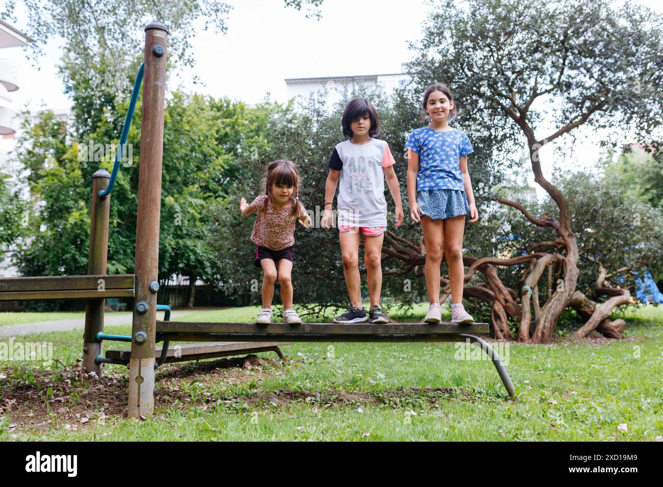 three children playing in the park jumping from the wooden bench Stock ...