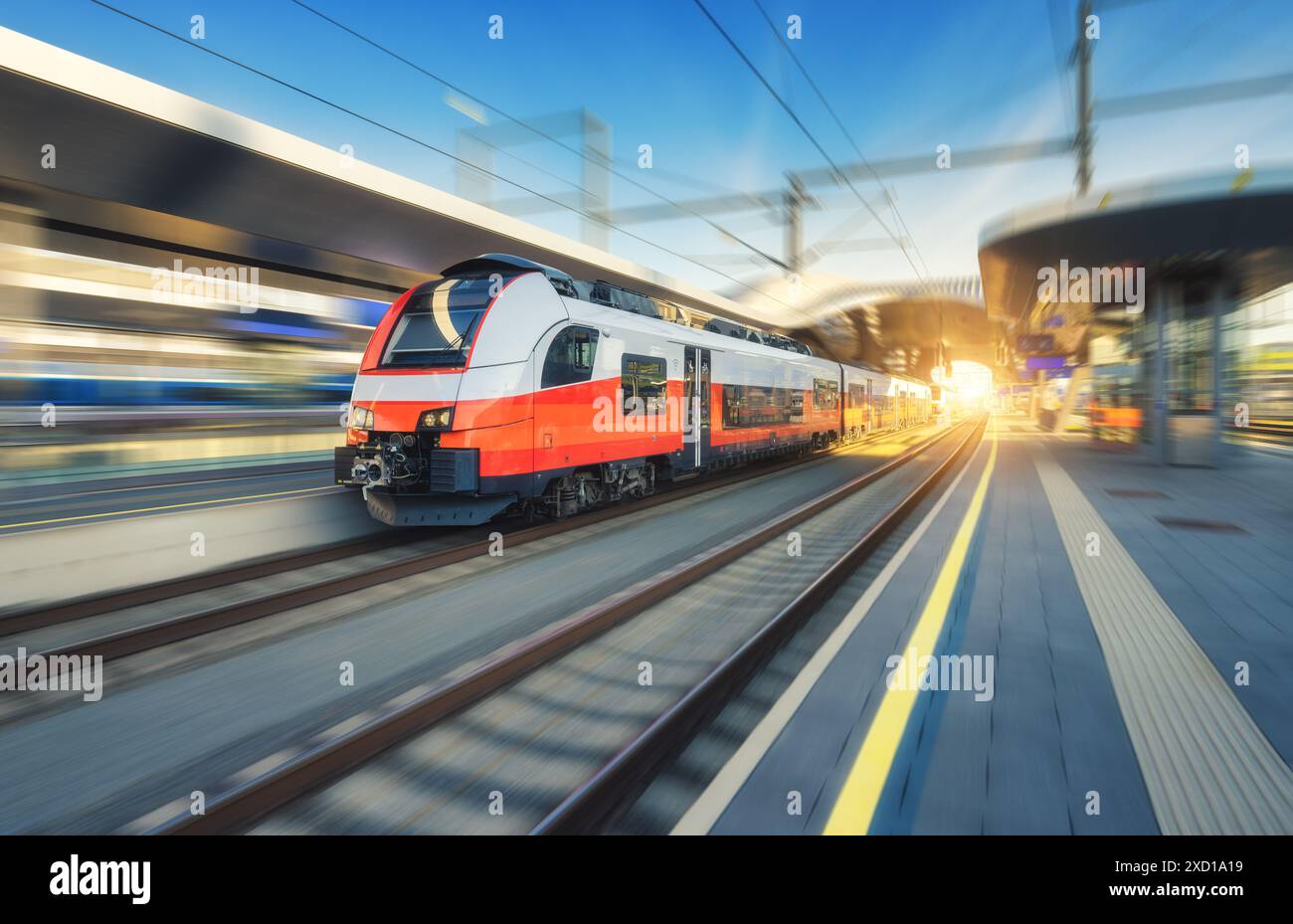 High-speed passenger train moving at railway station at sunset Stock ...