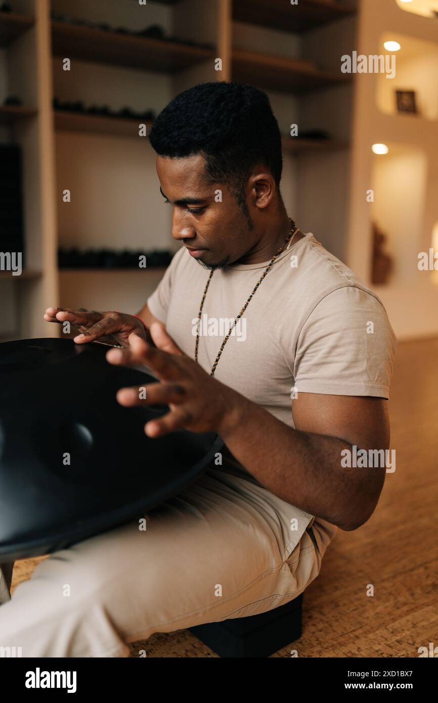 Closeup of focused African young man in trance sitting playing by hands ...