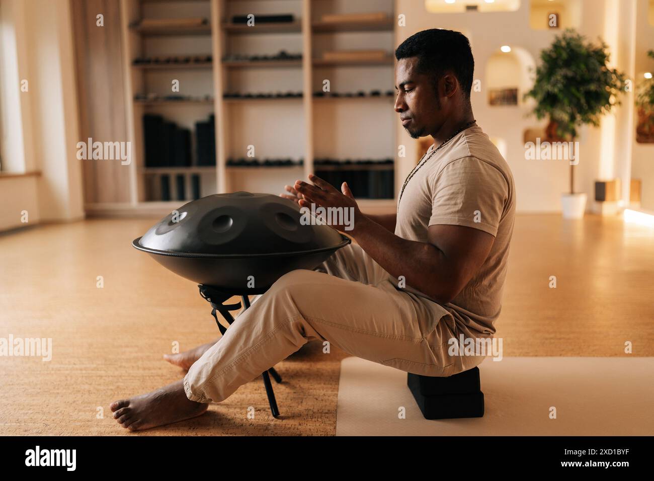 Side view of meditated black male in trance practicing native music ...