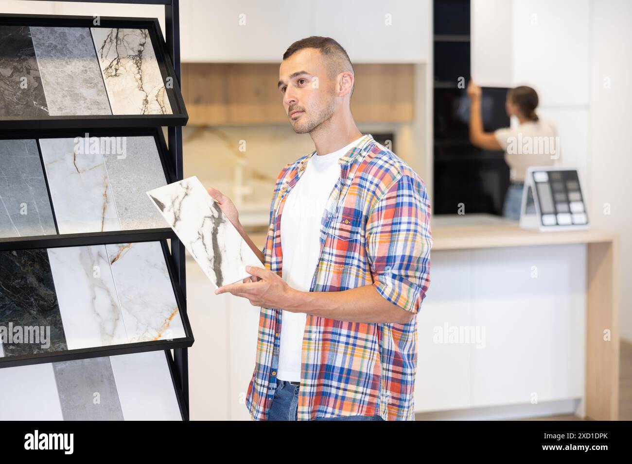 Young man chooses tiles in hardware store Stock Photo - Alamy