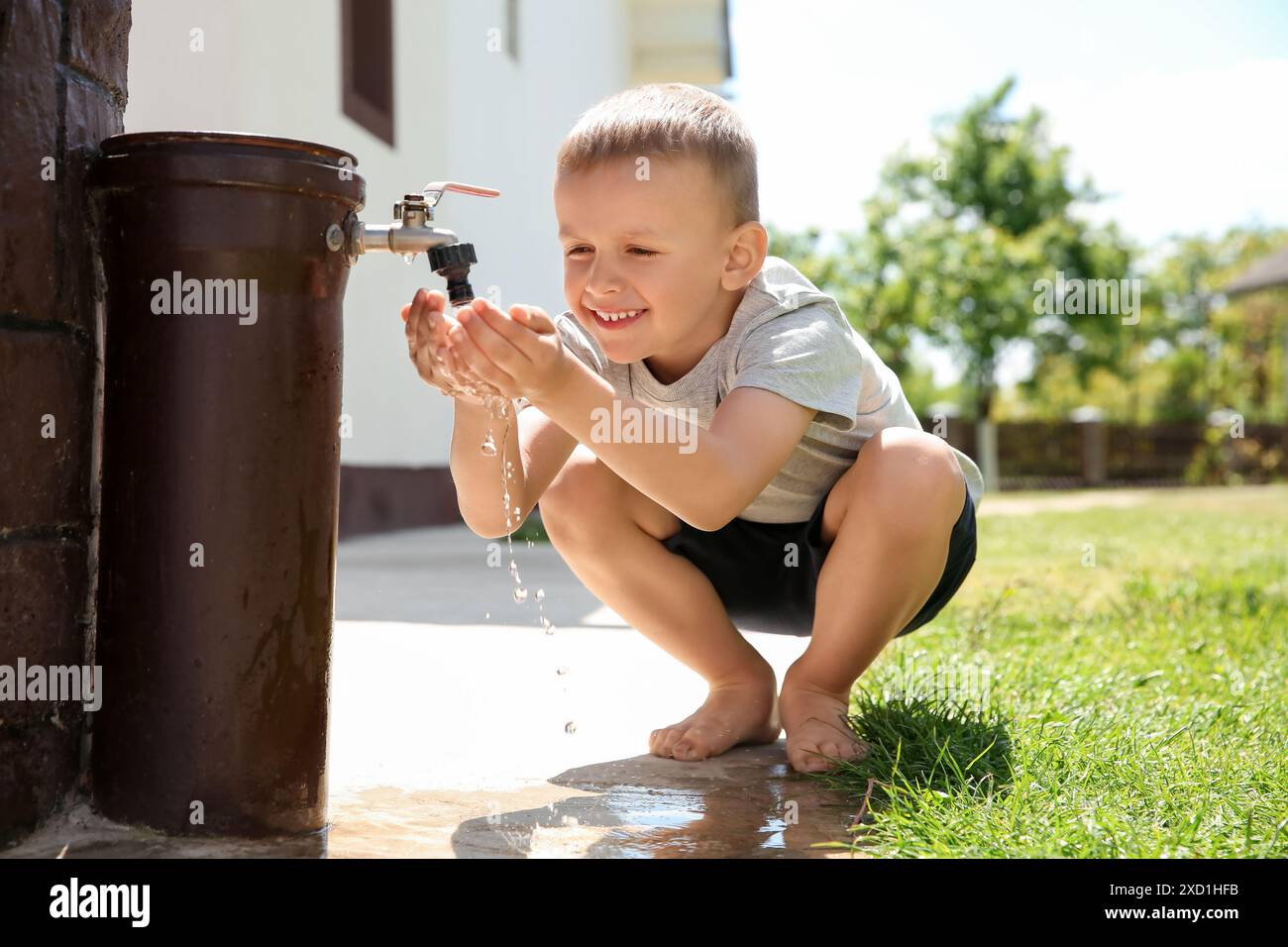 Water scarcity. Cute little boy drinking water from tap outdoors, space ...