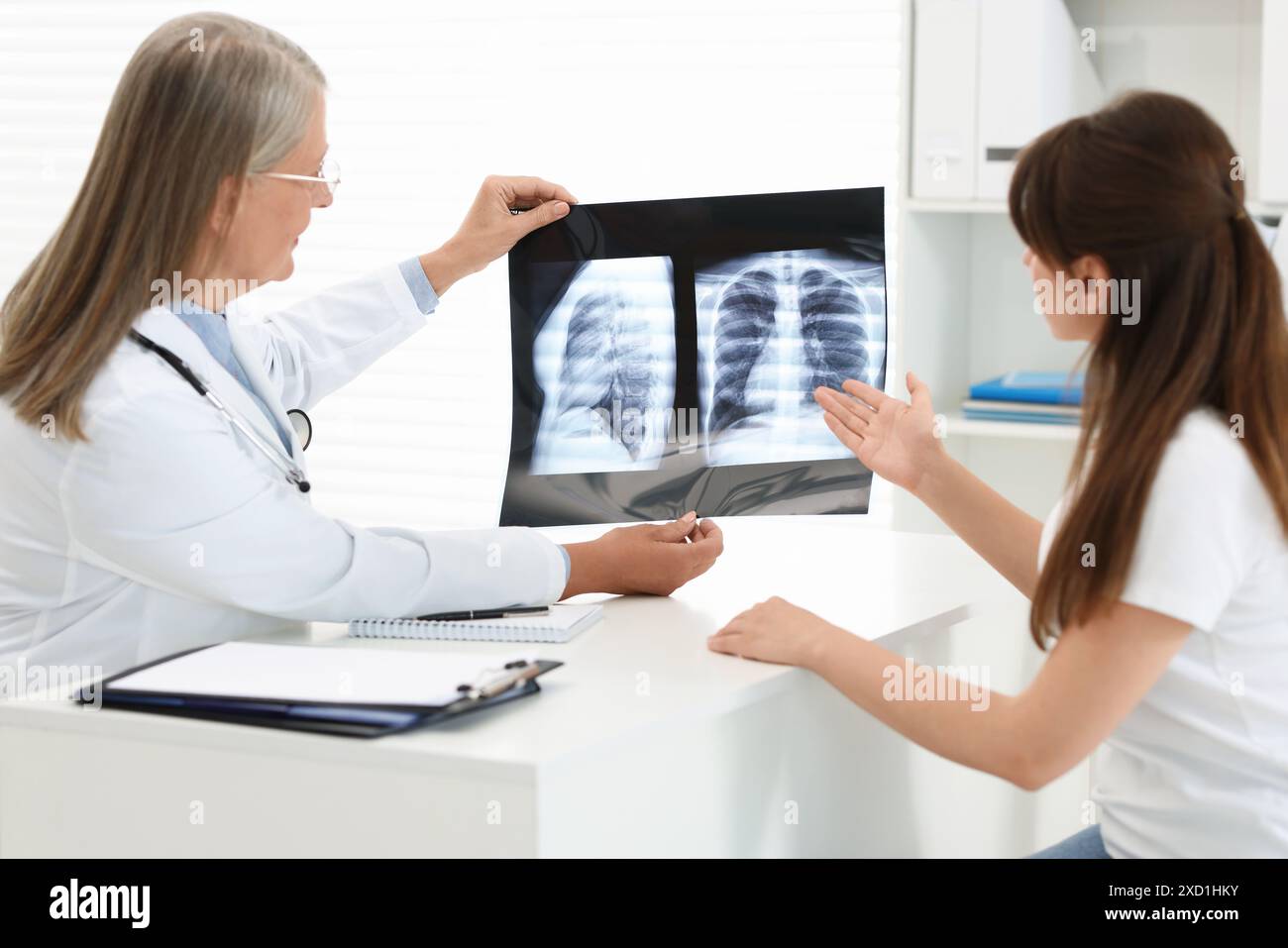 Lung disease. Doctor showing chest x-ray to her patient in clinic Stock ...