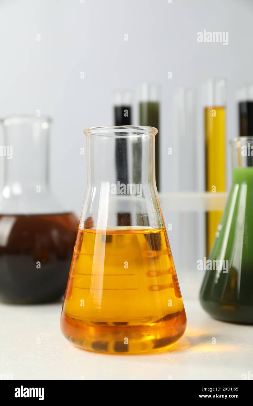 Laboratory glassware with different types of oil on white table ...