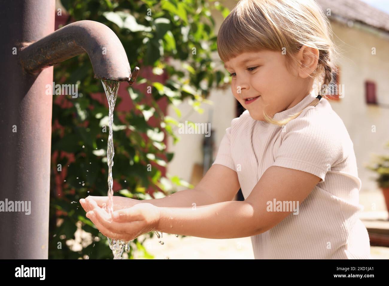 Water scarcity. Cute little girl drawing water with hands from tap ...